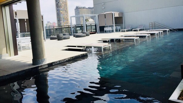 Uma piscina infinita interior com água cristalina, rodeada por espreguiçadeiras e um design arquitetônico moderno.