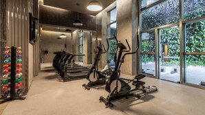 Uma academia com esteiras, bicicletas ergométricas e uma estrutura para pesos.