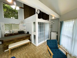Um espaço compacto com cozinha compacta, área de refeições e zona de estar com um banco e uma cadeira.