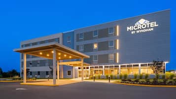 Um hotel moderno Microtel by Wyndham com entrada coberta, vários andares e fachada bem iluminada.