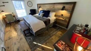 Quarto com cama, mesas de cabeceira, escrivaninha e cadeira.