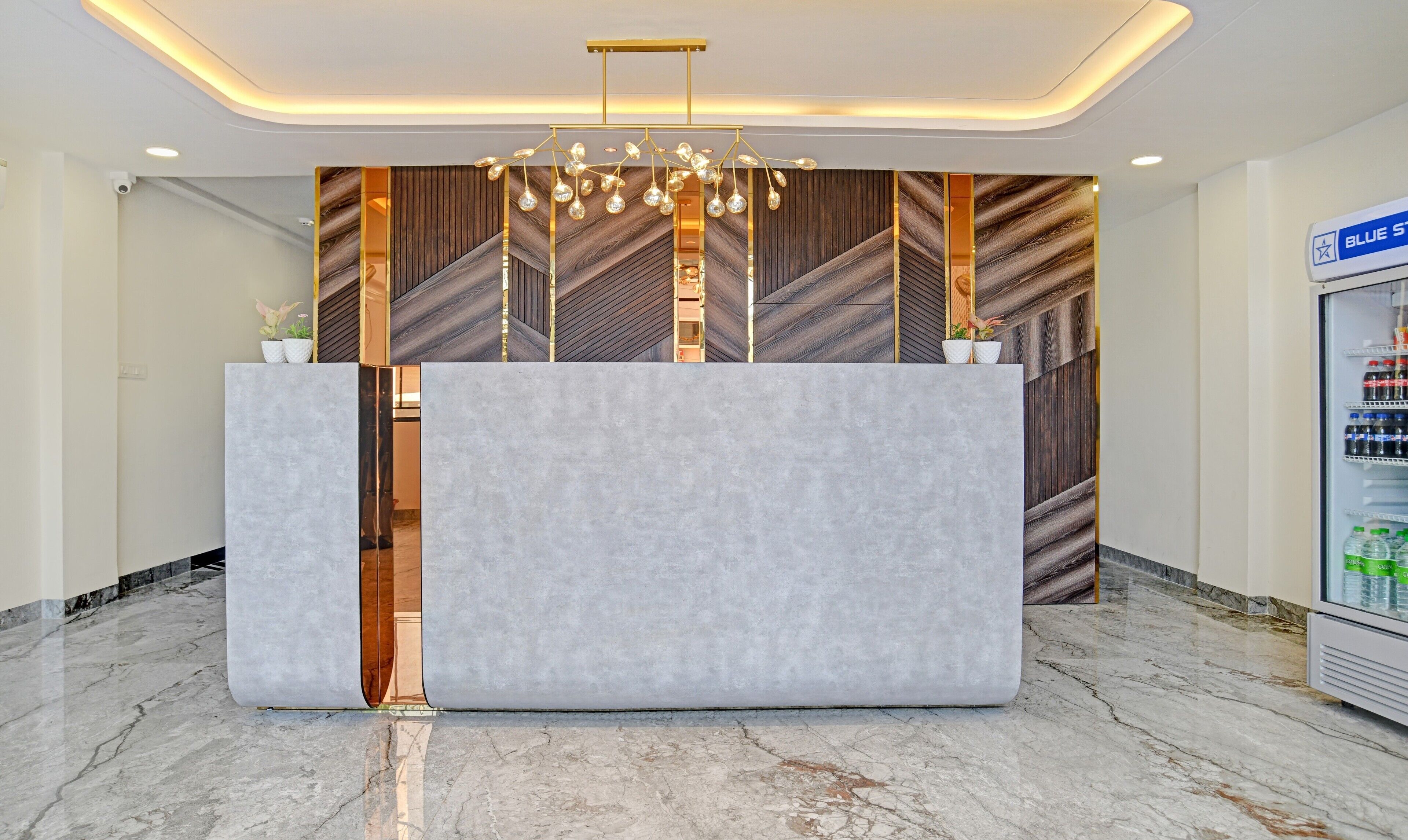 Uma receção com design moderno, um candelabro e uma parede com padrão geométrico.