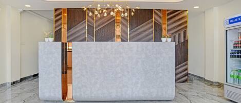 Uma receção com design moderno, um candelabro e uma parede com padrão geométrico.
