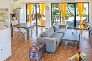 Uma sala de estar moderna com um sofá, uma mesa de jantar e um otomano colorido.