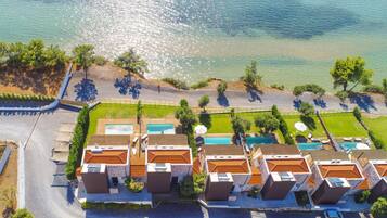 Vista aérea de um hotel à beira-mar, com vários edifícios, piscina e área de praia.