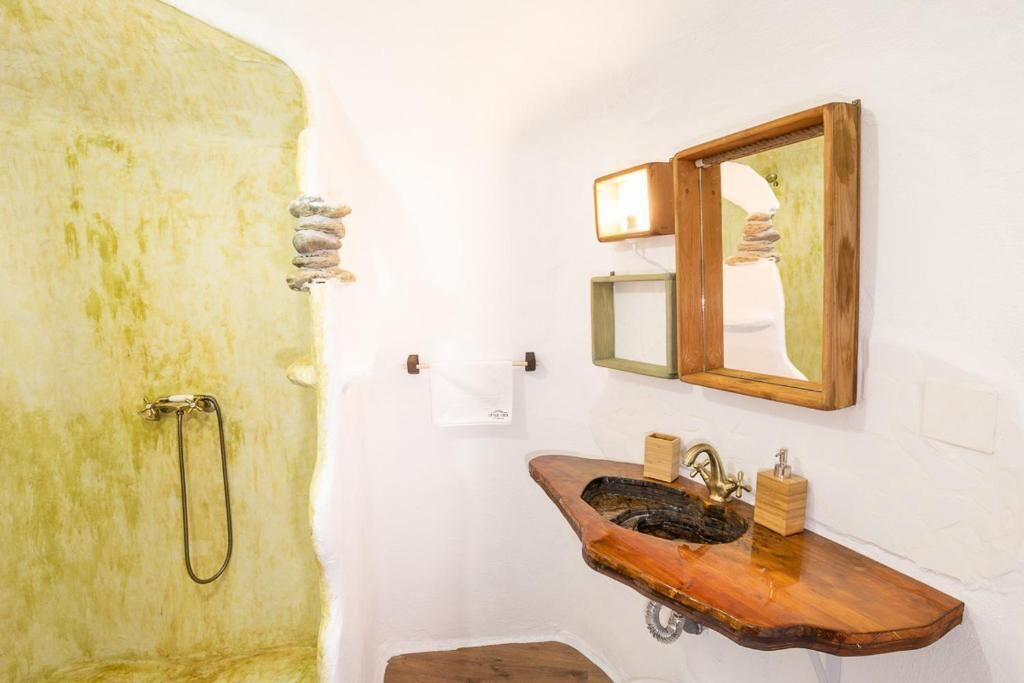 Uma casa de banho com toucador de madeira, lavatório, espelho e zona de duche.