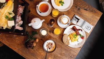 Uma mesa de café da manhã com diversos alimentos, um bule de chá e uma xícara.