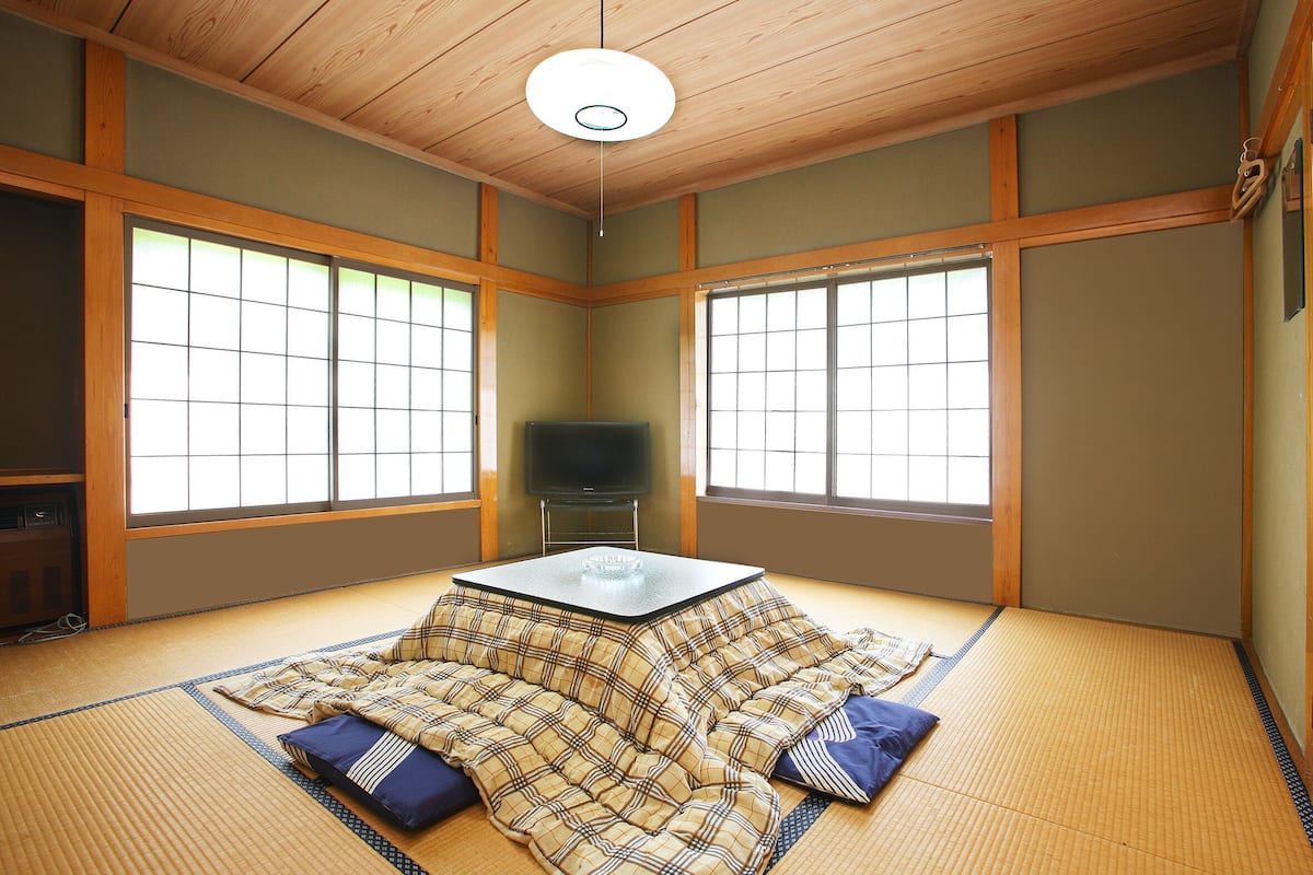 Um quarto com tatames, incluindo uma cama de tatame, uma pequena mesa e uma televisão.