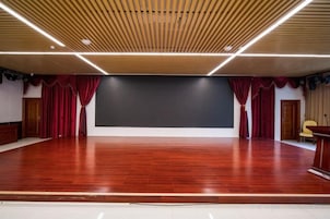 Um espaço interno com palco, cortinas e um pódio.