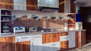 Cozinha com armários de madeira, painel de azulejos e diversos eletrodomésticos, incluindo uma torradeira e um liquidificador.