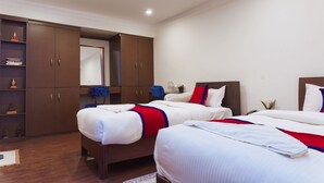 Quarto de hotel com duas camas, um guarda-roupa e um espelho.