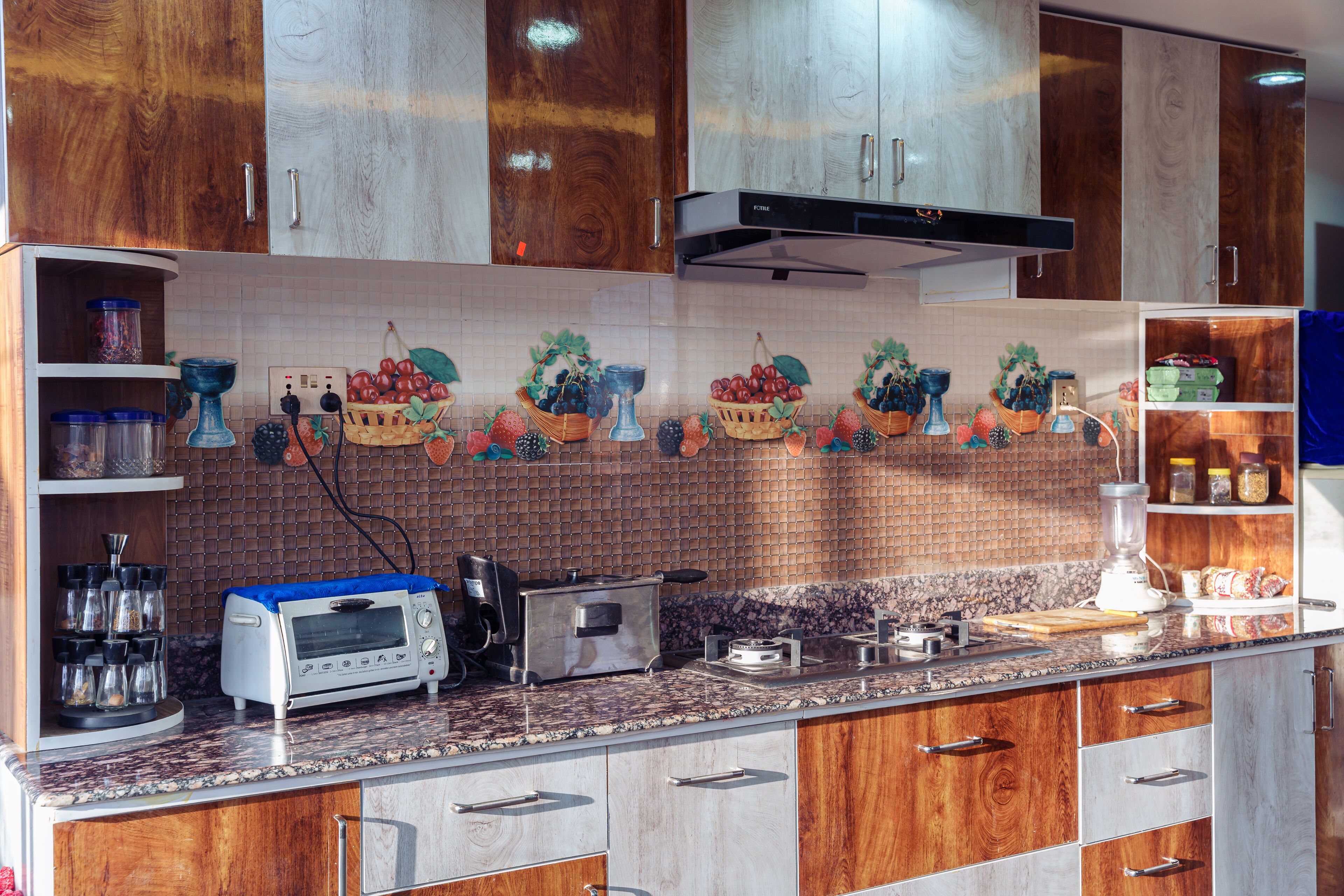 Uma cozinha com armários de madeira, micro-ondas, torradeira e liquidificador na bancada.