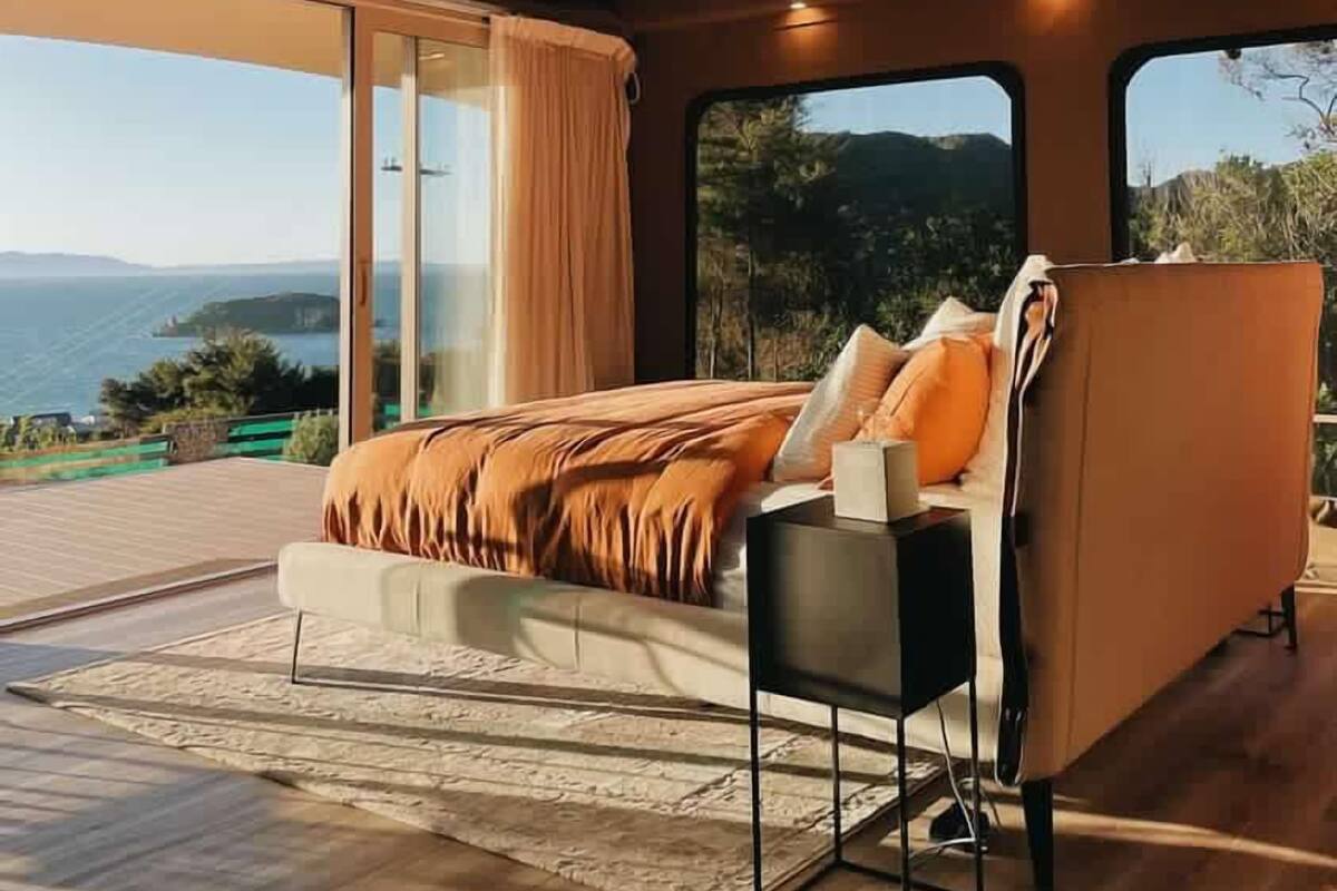 Quarto com uma cama grande, vista para o mar e varanda.