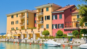 Hotel à beira-mar com várias varandas, área de piscina e barcos.