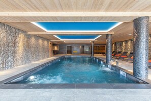 Uma piscina interior com design moderno, incluindo uma clarabóia e painéis de mosaicos.
