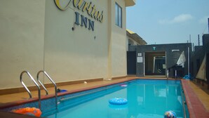 Piscina com um letreiro indicando 'Carthay's Inn' no prédio.
