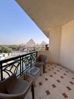 Varanda com vista para pirâmides, uma mesa e duas cadeiras.