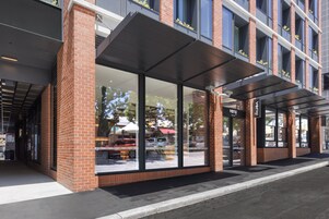 Um edifício moderno com grandes janelas e uma área de entrada coberta.