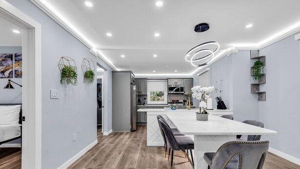 Cozinha moderna com ilha central, cadeiras estofadas em cinza e iluminação pendente.