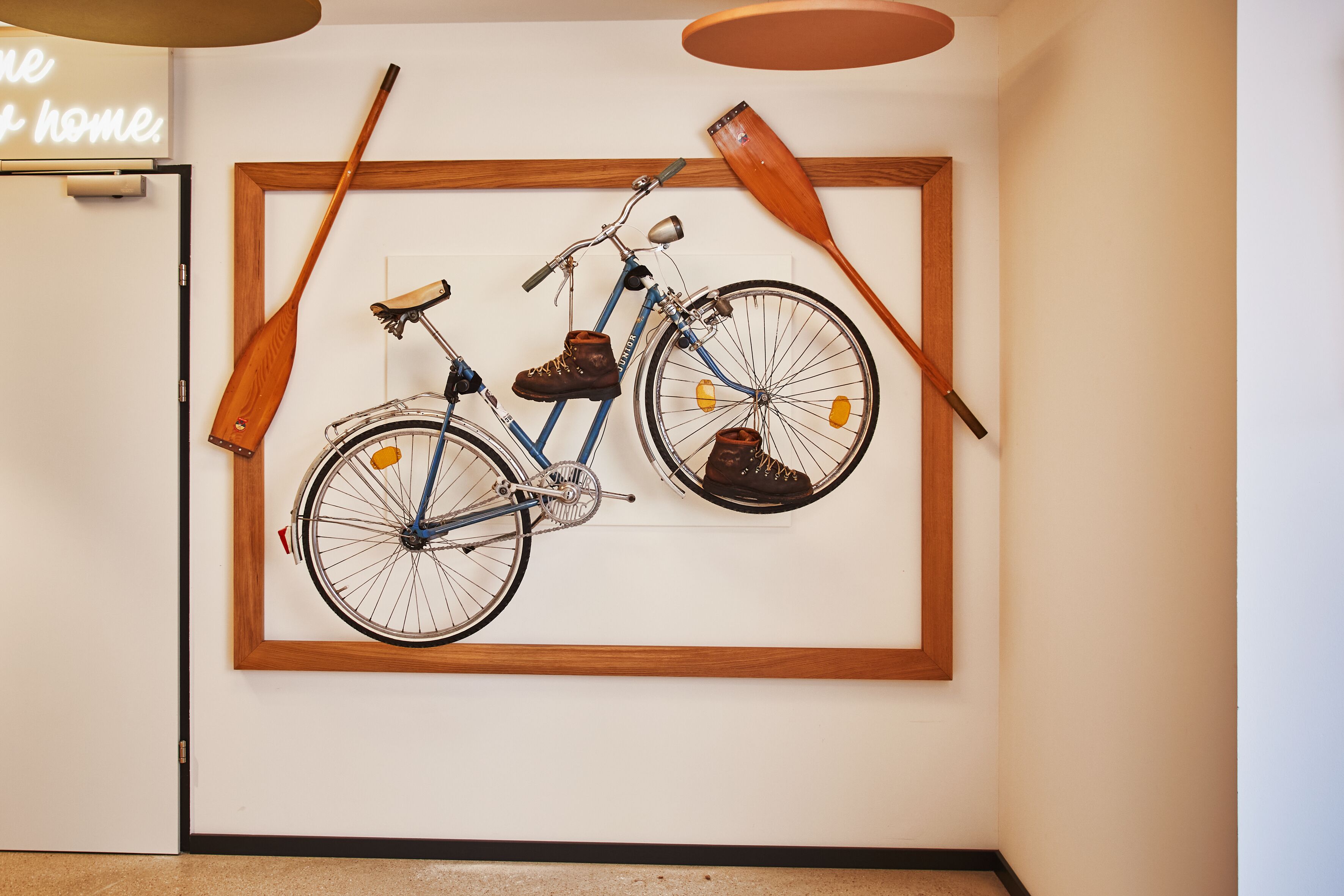 Um quarto com uma bicicleta emoldurada e dois remos de madeira pendurados na parede.