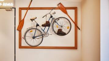 Um quarto com uma bicicleta emoldurada e dois remos de madeira pendurados na parede.