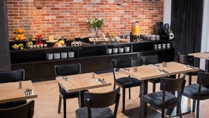 Um restaurante com paredes de tijolo, mesas de madeira e cadeiras pretas.