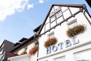 Um hotel com fachada tradicional em estilo enxaimel, várias janelas e floreiras.