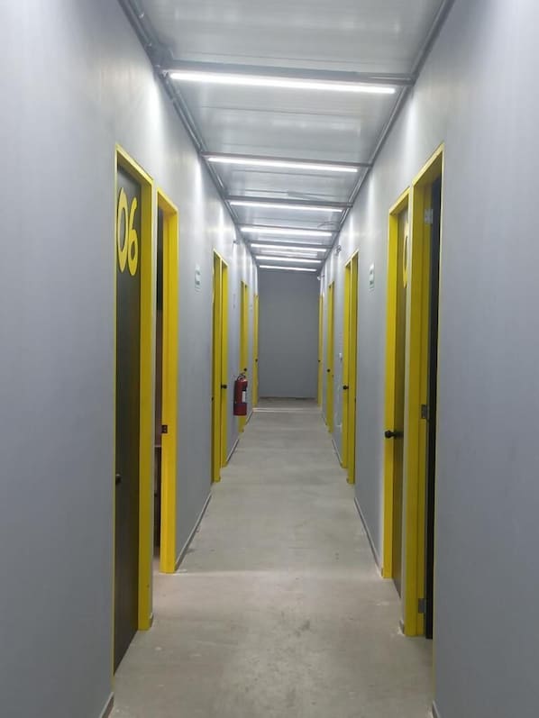 Um corredor comprido e estreito, com portas em ambos os lados, cada uma delas identificada com um número.