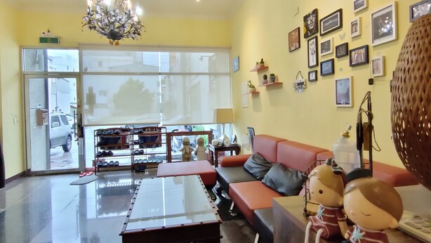 Ampla sala de estar com lustre, sofá, mesa de centro e parede decorada com quadros.