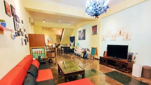Sala de estar com um sofá vermelho, uma mesa de centro de madeira, uma televisão e um candelabro.