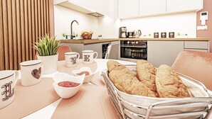 Uma cozinha moderna com área de refeições, apresentando uma cesta de pão, xícaras de café e uma planta.