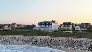 Uma área residencial costeira com casas, um muro de pedra e uma praia.