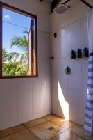 Casa de banho com janela, chuveiro e chão em mosaico.