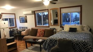 Um quarto aconchegante com uma cama grande, um sofá, uma mesa de jantar e um ventilador de teto.