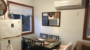 Cozinha compacta com mesa, cadeiras, geladeira e ar-condicionado.