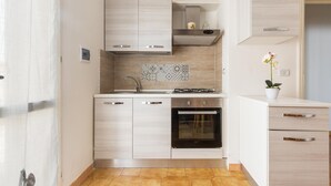 Cozinha moderna com armários de madeira clara, fogão a gás, forno e pia.