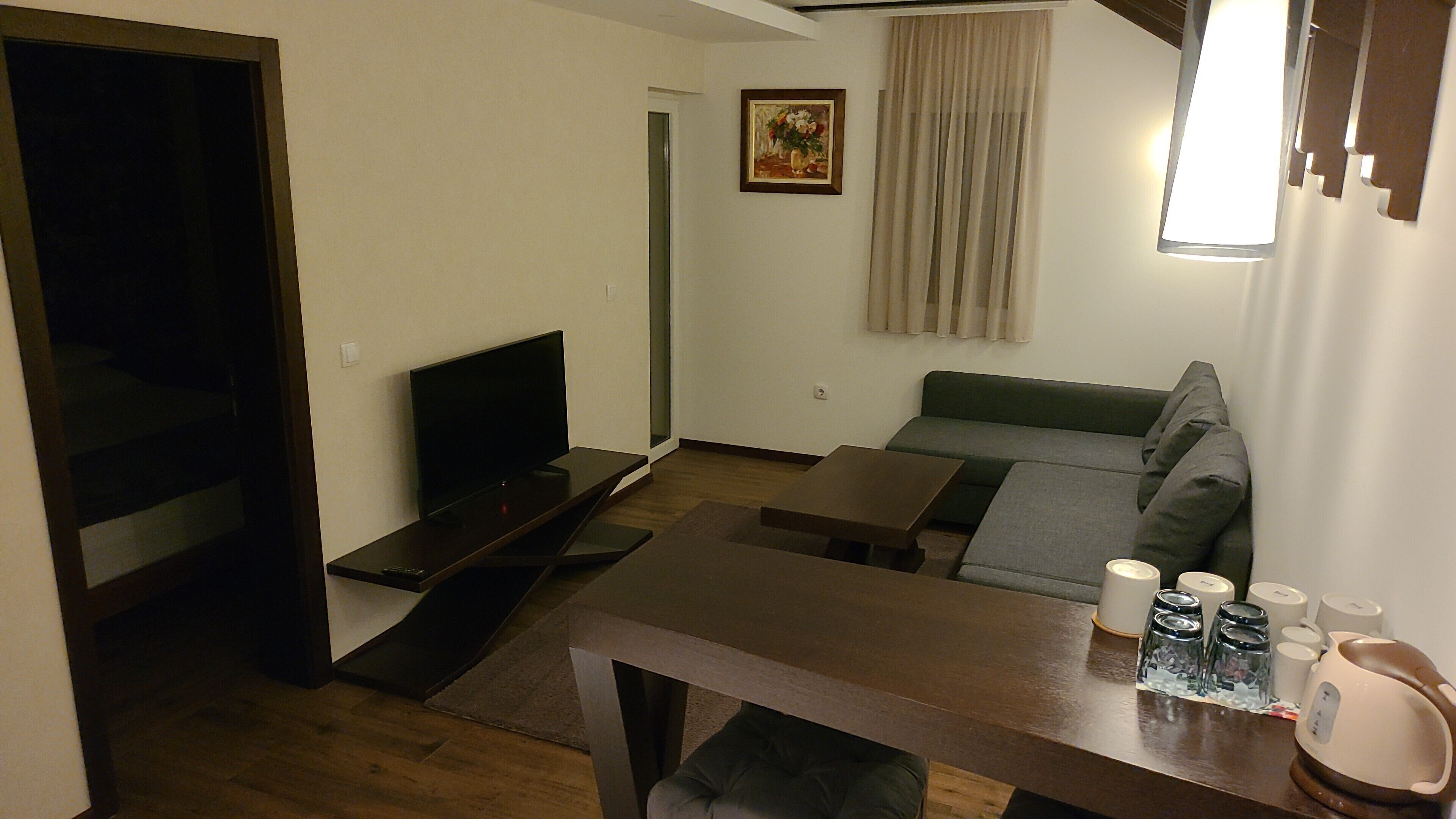Uma sala de estar com sofá, mesa de centro, televisão e um quadro na parede.
