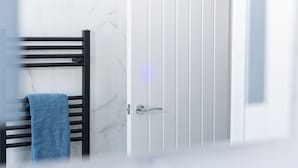 Casa de banho com porta-toalhas, toalha e porta com linhas verticais.