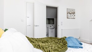Quarto com uma cama, um cobertor verde e uma toalha azul.