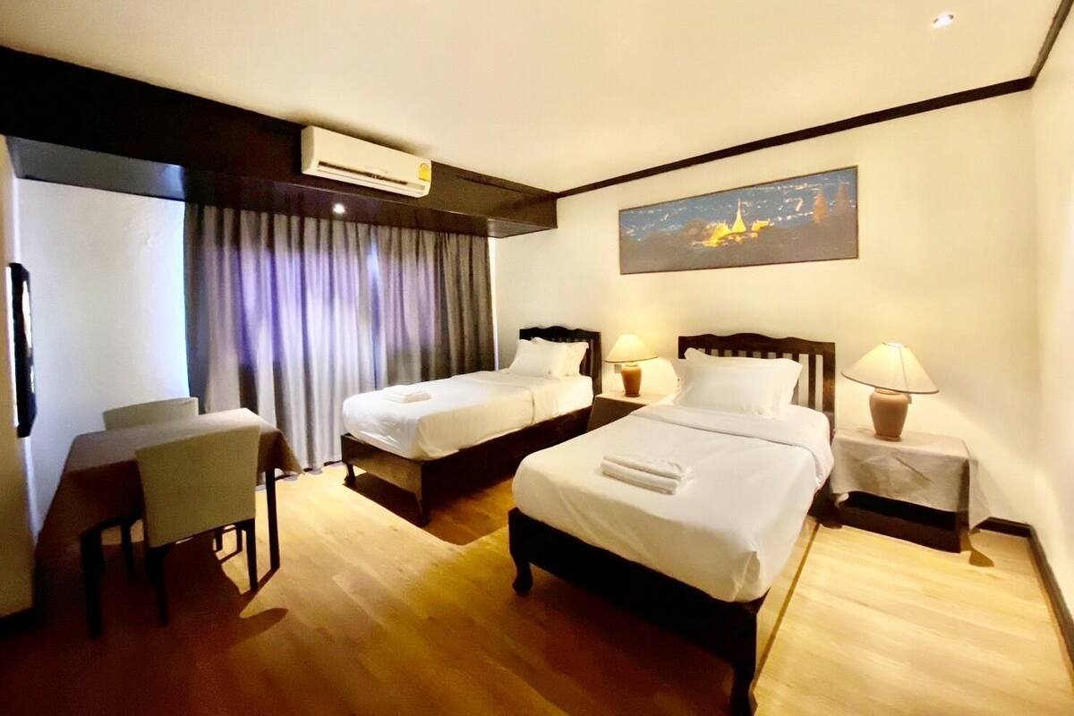 Quarto de hotel com duas camas, uma escrivaninha e uma cadeira.