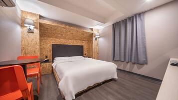 Quarto de hotel com uma cama, uma escrivaninha e duas cadeiras.