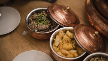 Uma mesa de madeira com várias tigelas de cobre contendo comida, algumas com tampas.