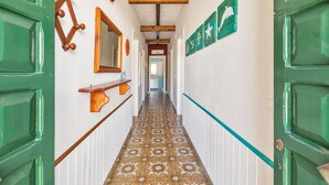 Um corredor com portas verdes, piso estampado e decorações fixadas na parede.