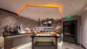 Uma cozinha moderna com um serviço de buffet, máquina de café e diversas opções de comida.