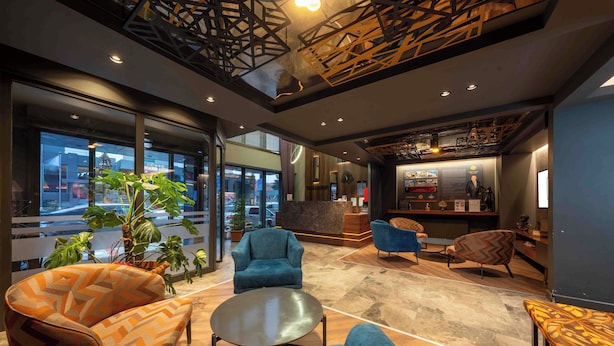 Um lobby moderno com assentos, uma recepção e uma grande janela com vista para o exterior.