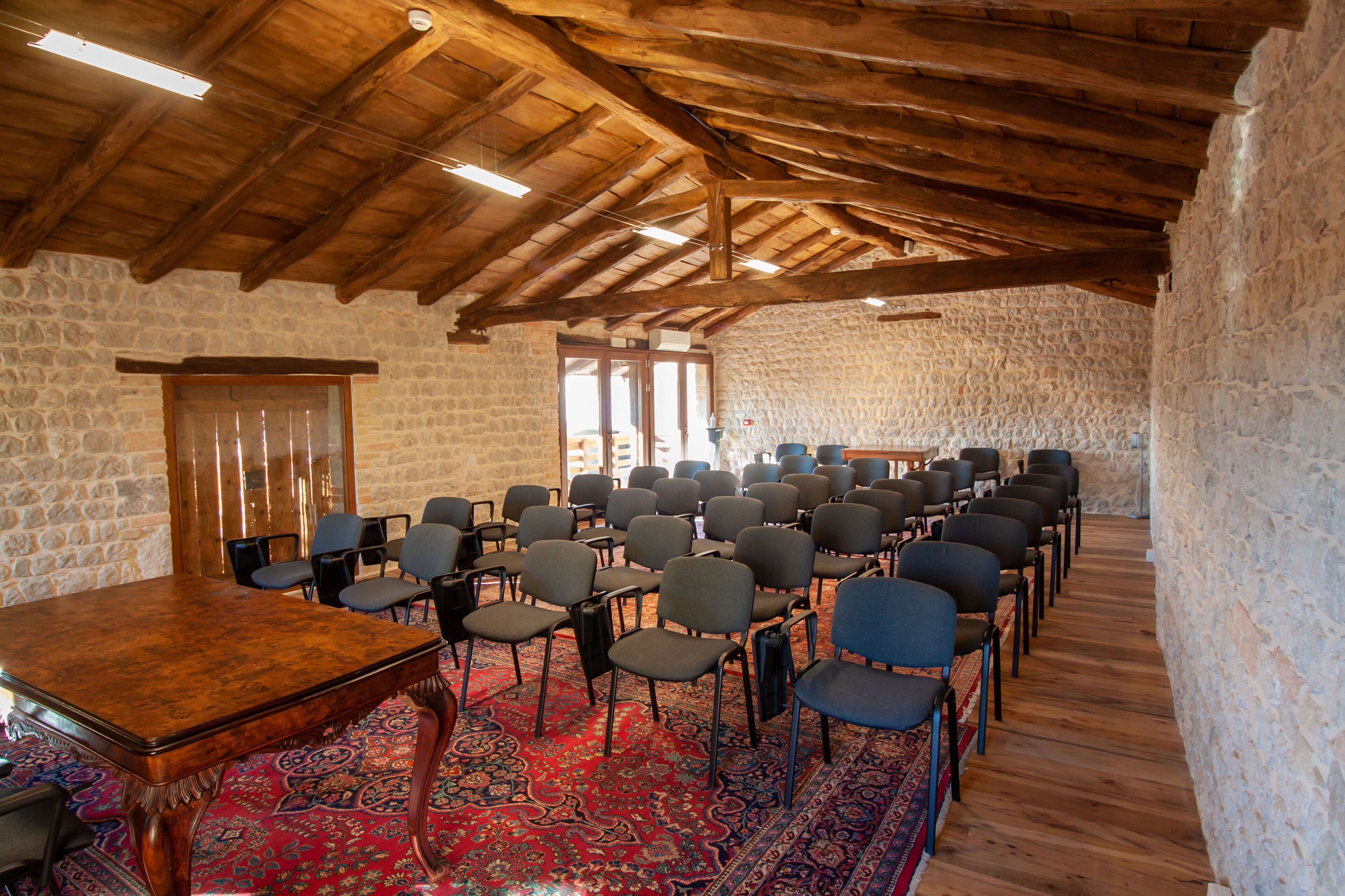 Uma sala de conferências com uma mesa de madeira e cadeiras dispostas para uma reunião.