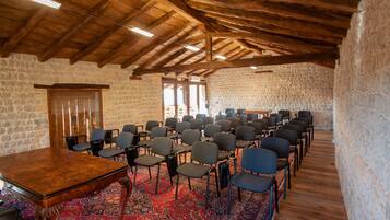 Uma sala de conferências com uma mesa de madeira e cadeiras dispostas para uma reunião.