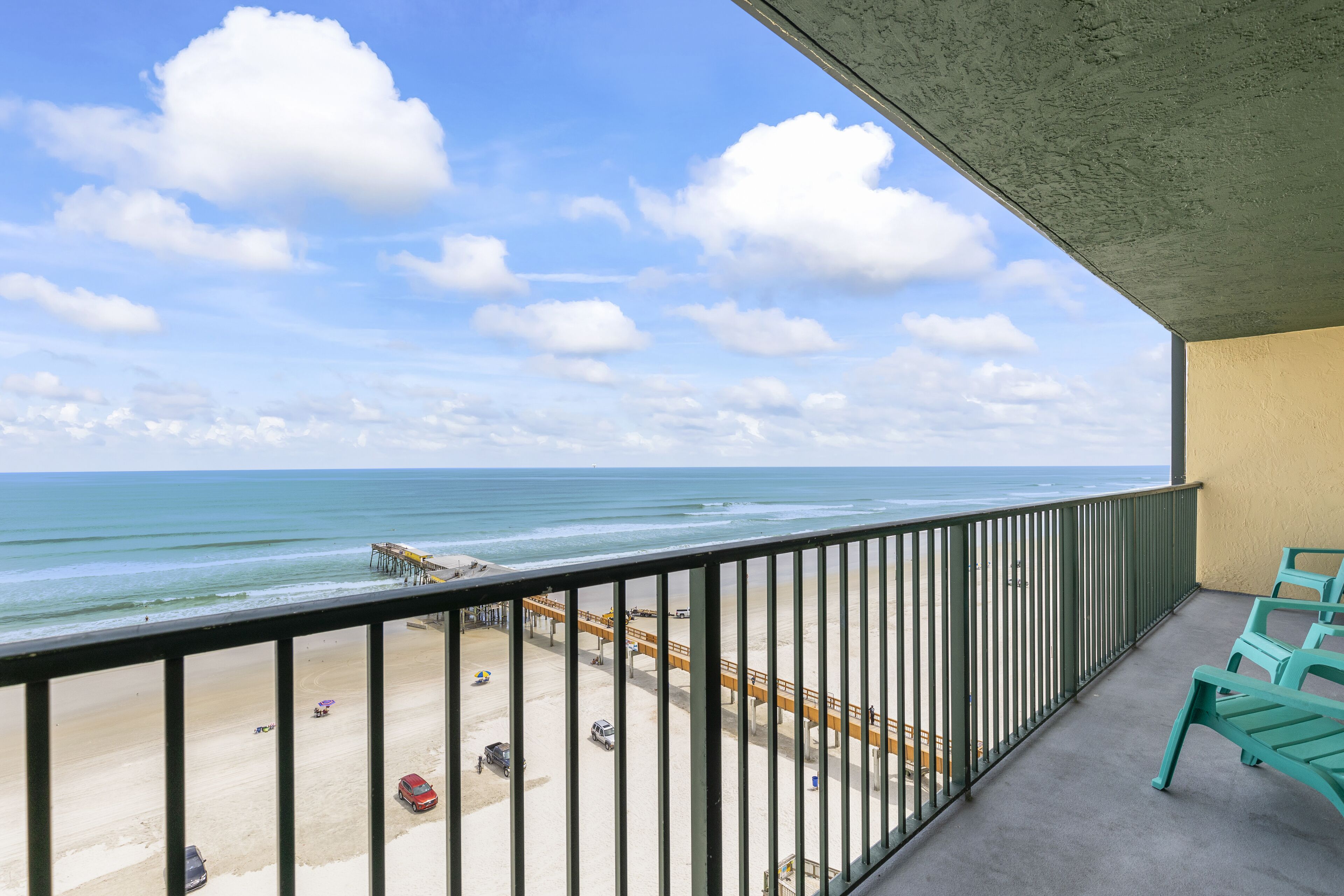 Varanda com vista para a praia, um cais e céu claro.