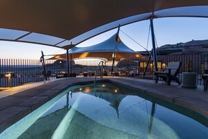 Área da piscina com espaço de estar coberto, piscina e vista para a paisagem.