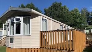Uma casa móvel com um deck de madeira e área cercada.